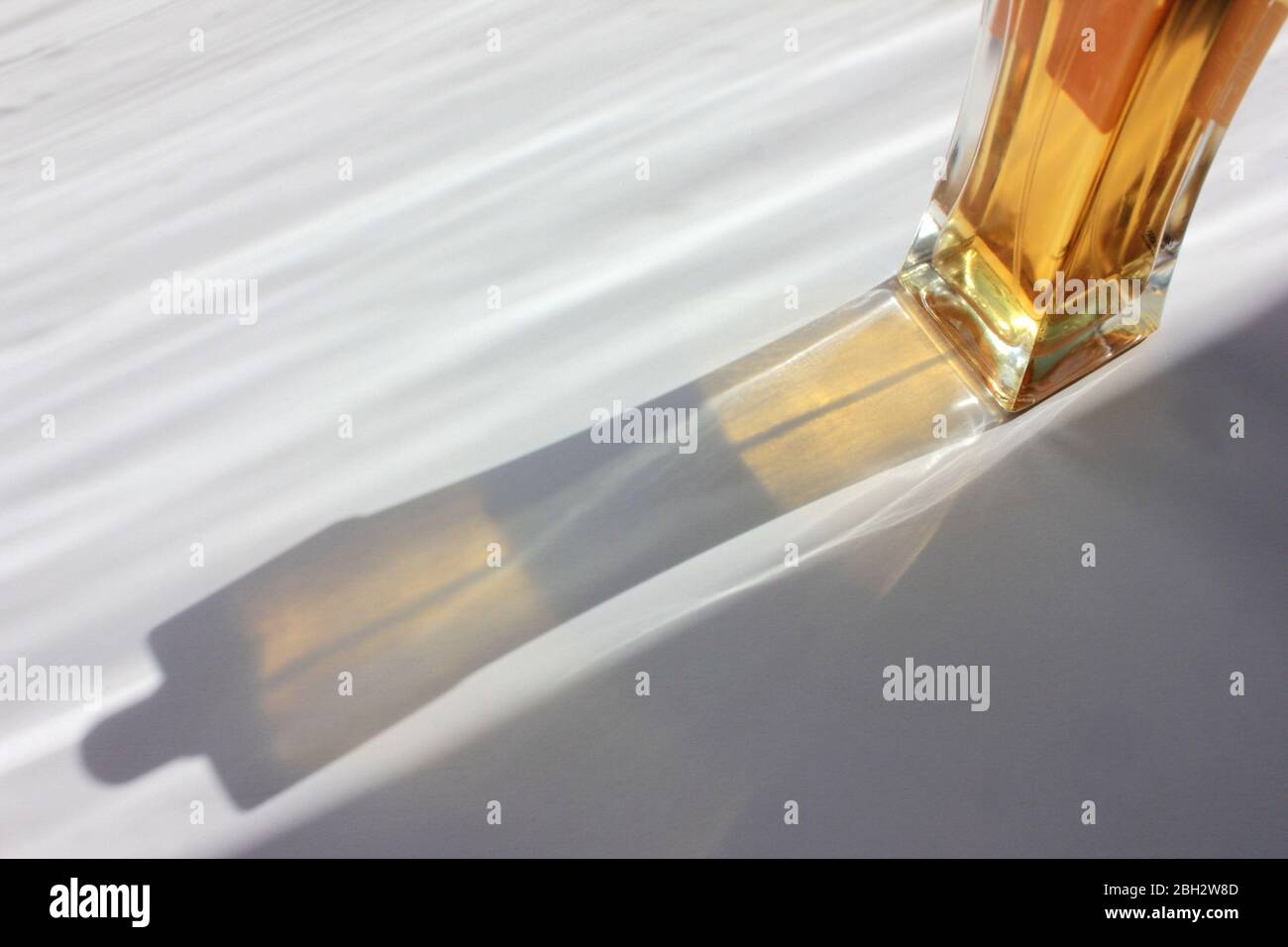 Fragment of perfume spray bottle in sunlight with long colored shadow ...