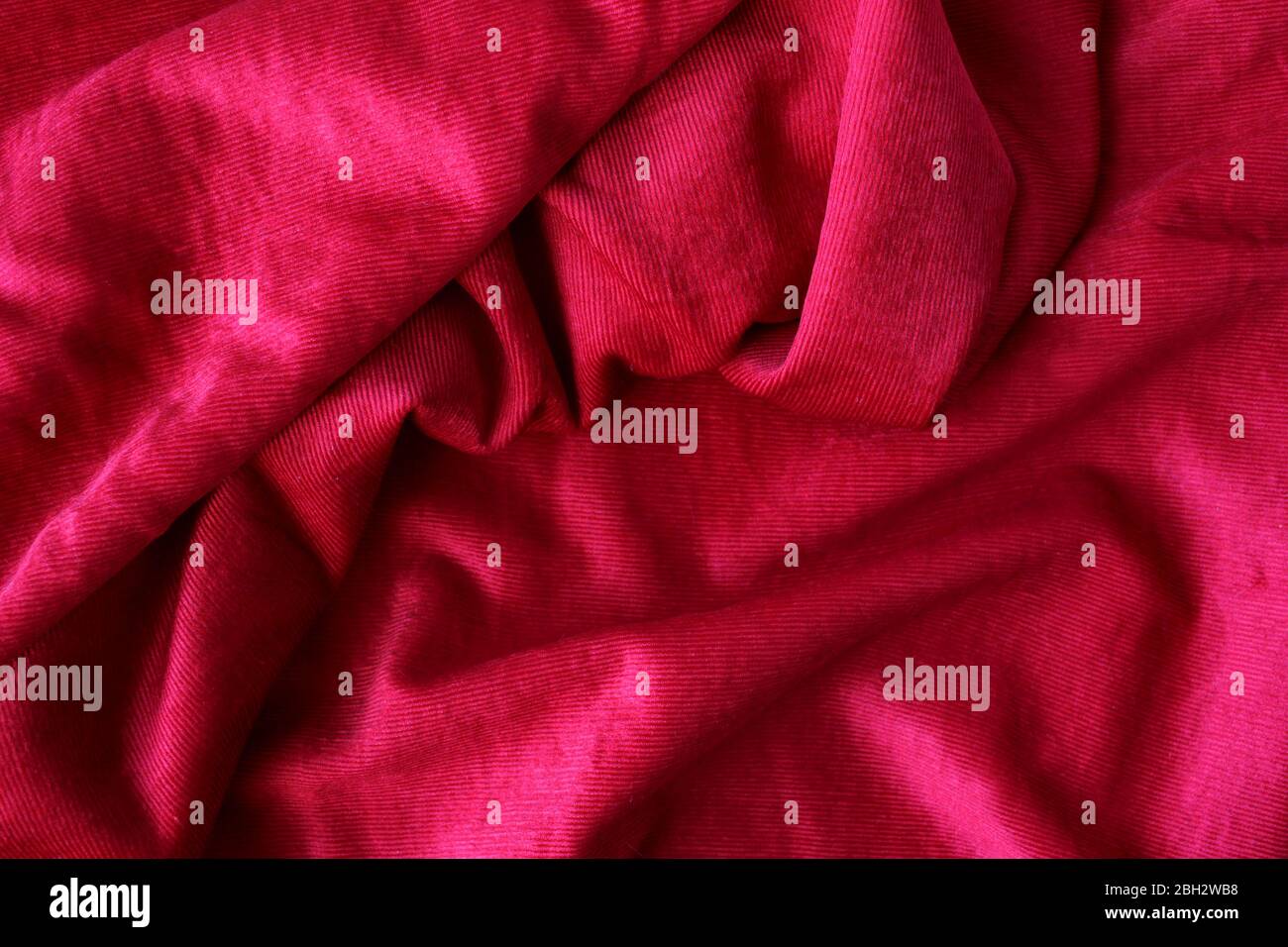 Red velvet fabric wavy folds for background texture. Fragment of a soft ...