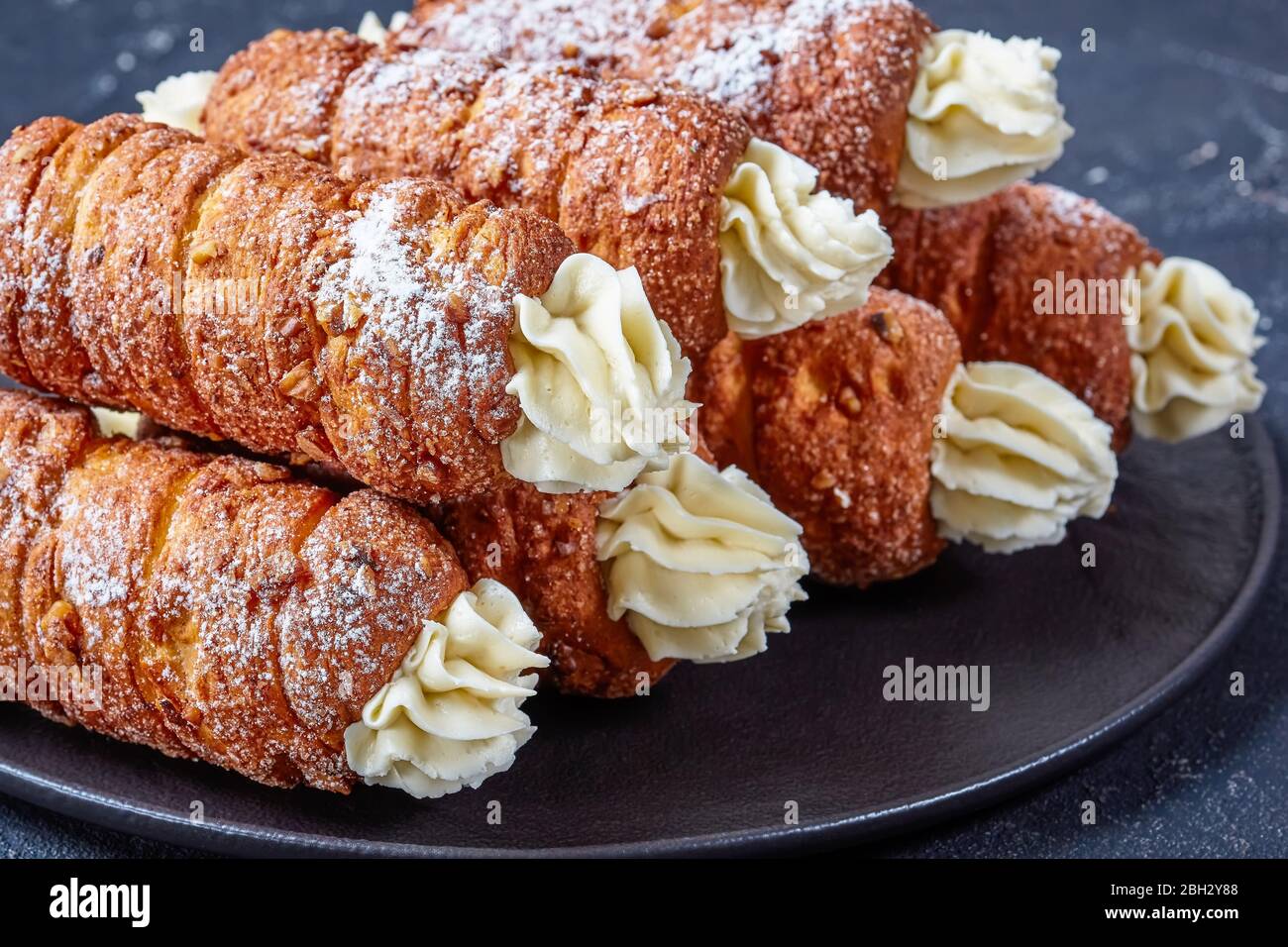 Cinnamon chimney cakes decorated with swirls of buttercream sprinkled ...
