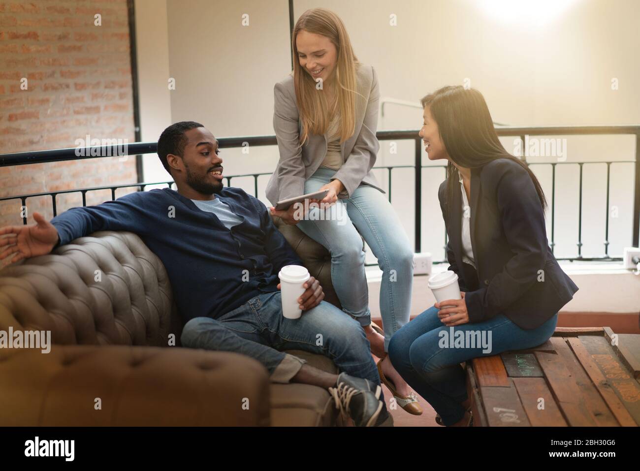 Attractive co workers talking sitting on sofa with tablet Stock Photo ...