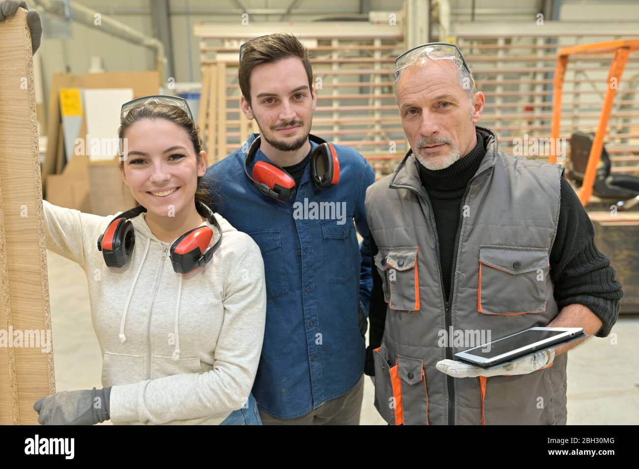 Portrait of man with trainees in carpentry warehouse Stock Photo - Alamy