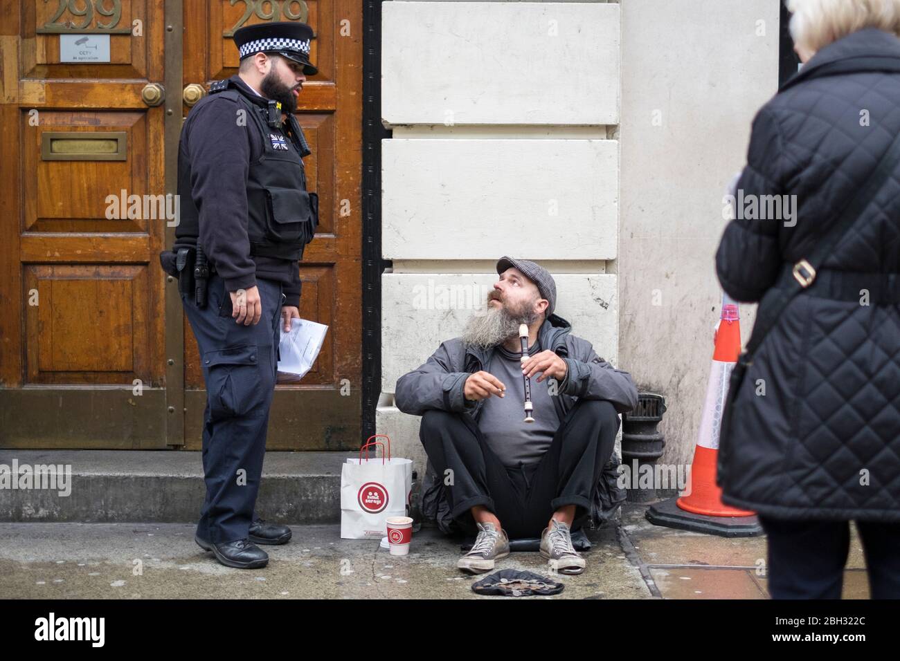 A police officer speaking with a man illegally busking on the recorder ...
