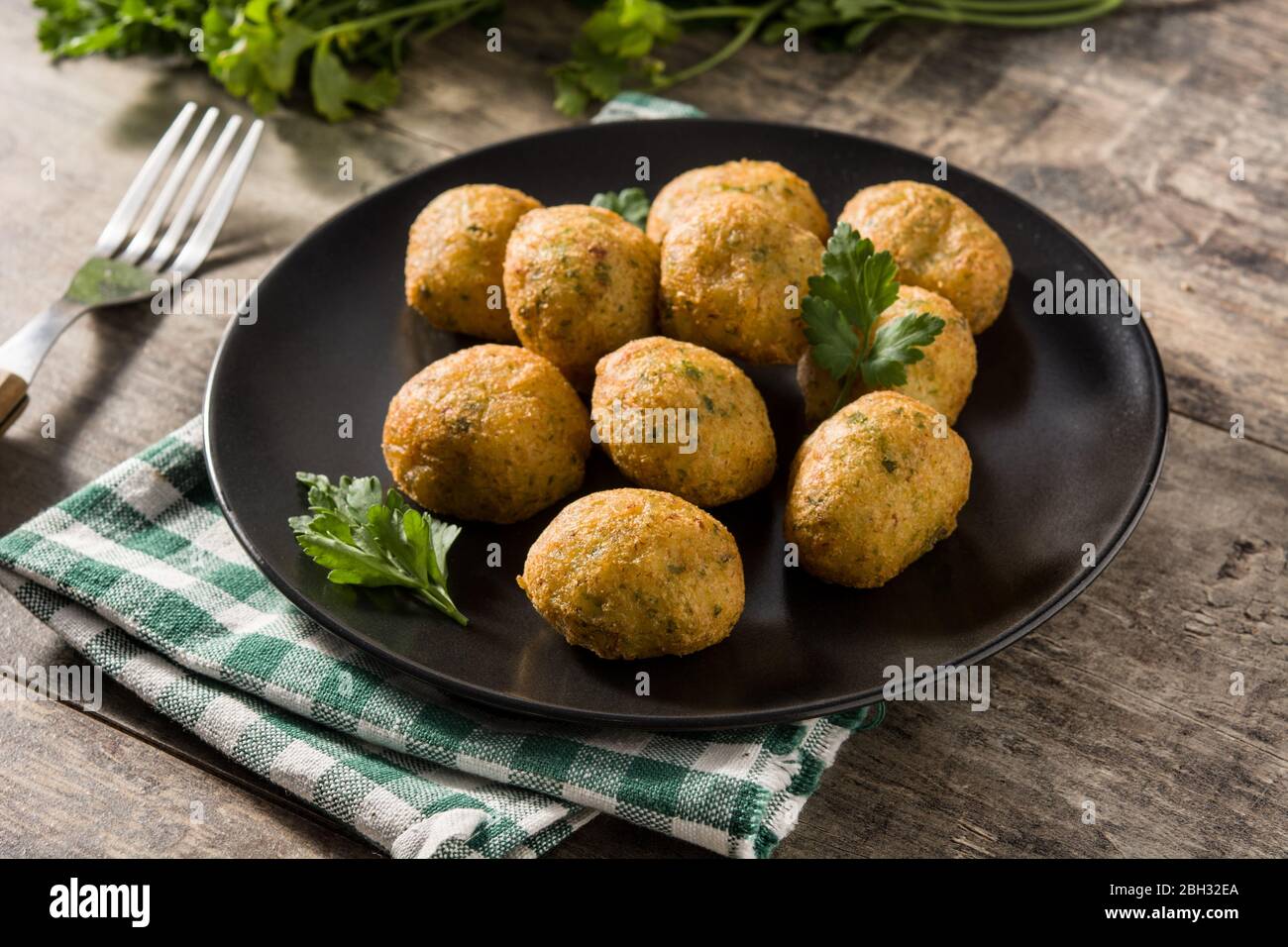 Traditional cod fritters decorated with garlic and parsley on wooden ...