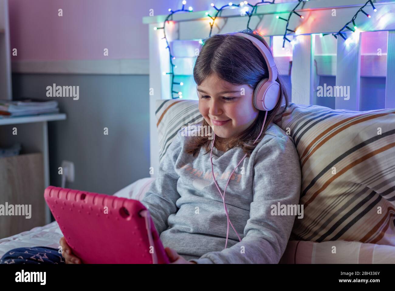 Cute little girl using tablet while lying in bed Stock Photo - Alamy
