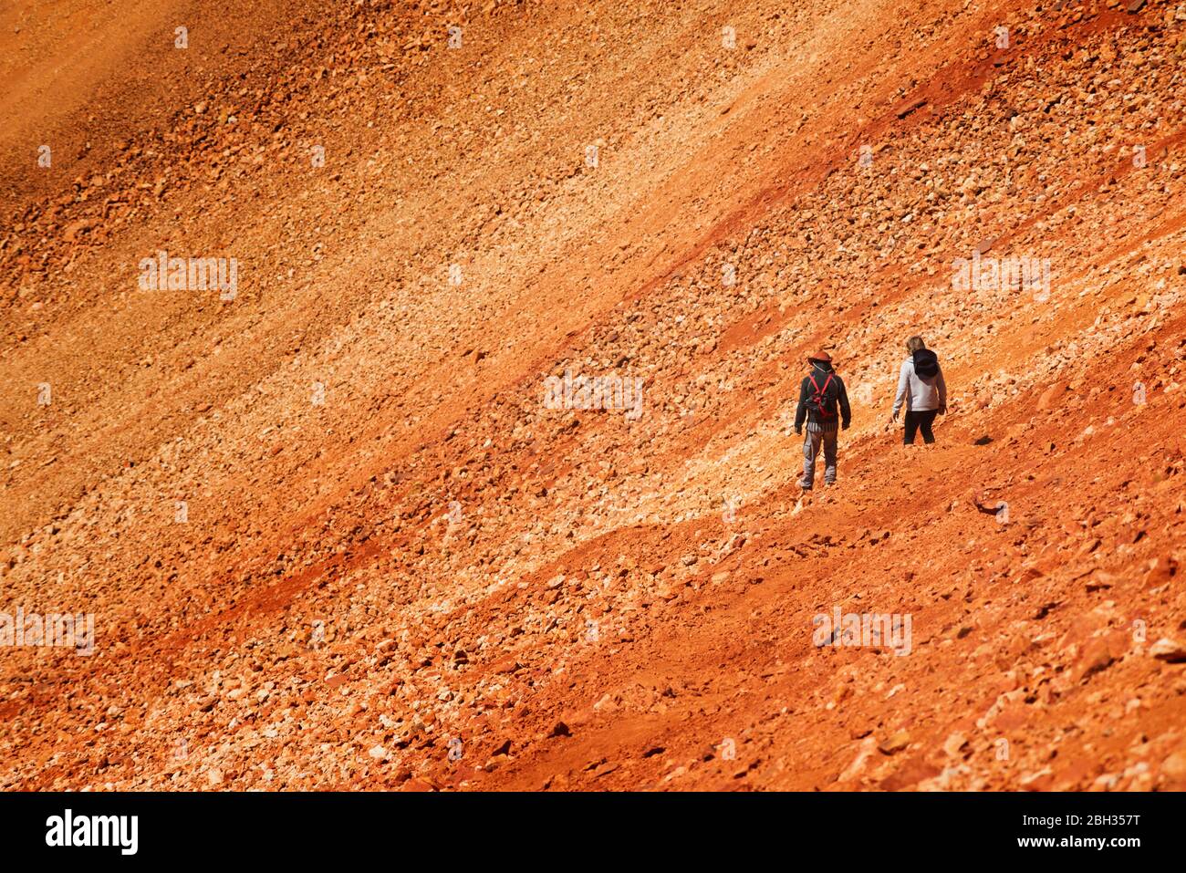 two tourists on steep volcanic slope of Tunupa volcano in Bolivia Stock ...