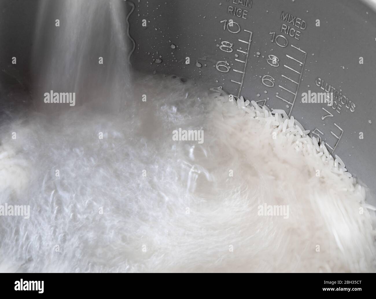 Rice prepared for cooking in an electric rice cooker Stock Photo - Alamy