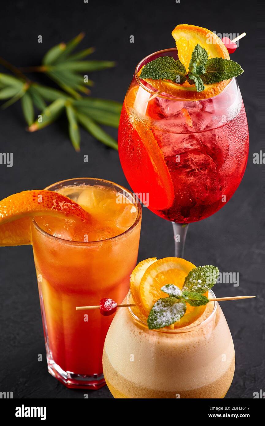 Three alcoholic cocktails, red, orange and yellow colors on black ...