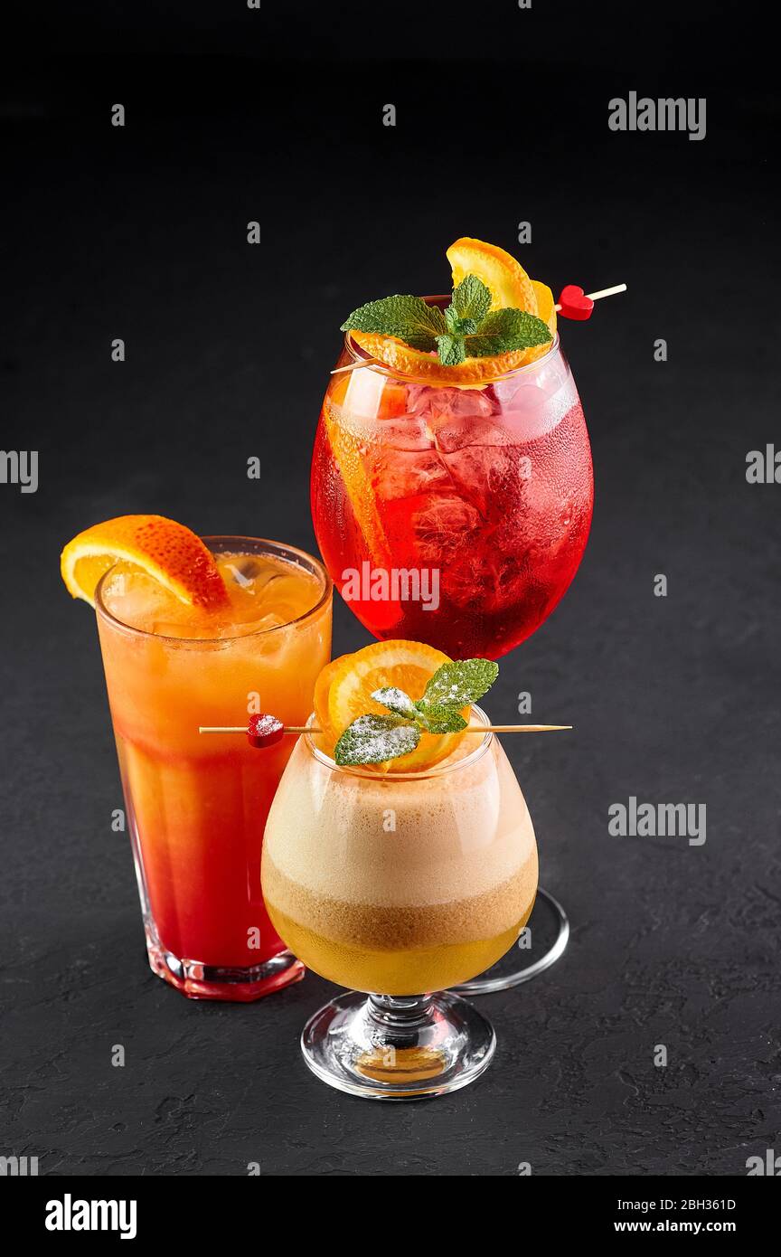 Three alcoholic cocktails, red, orange and yellow colors on black ...