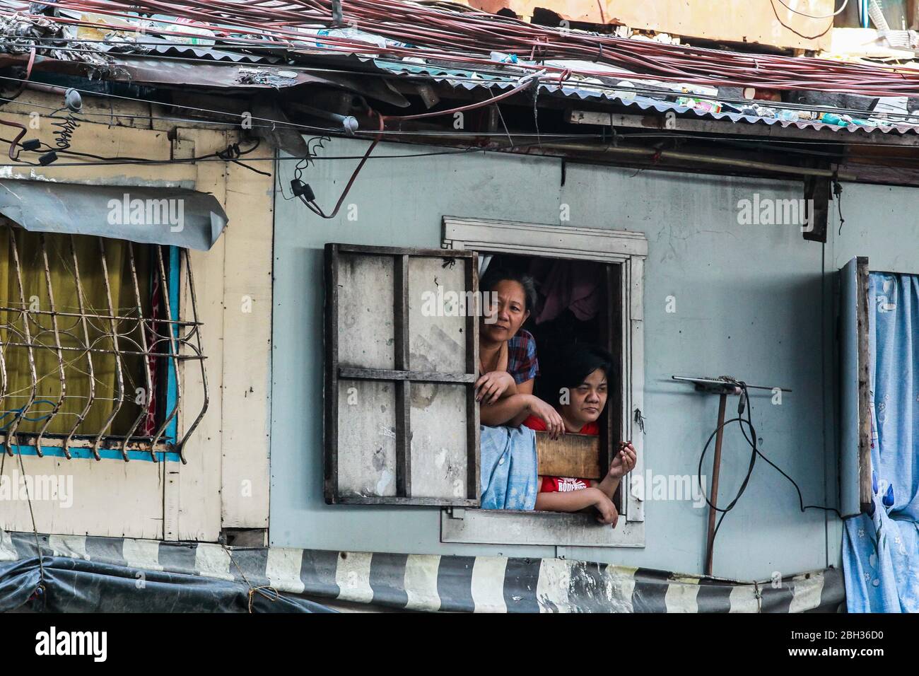 Quezon City. 23rd Apr, 2020. Residents look out of the window of their ...