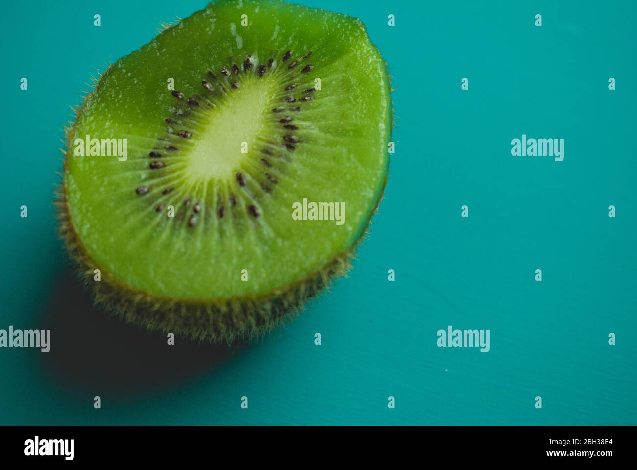 photograph of half of one kiwi on turquoise background Stock Photo - Alamy