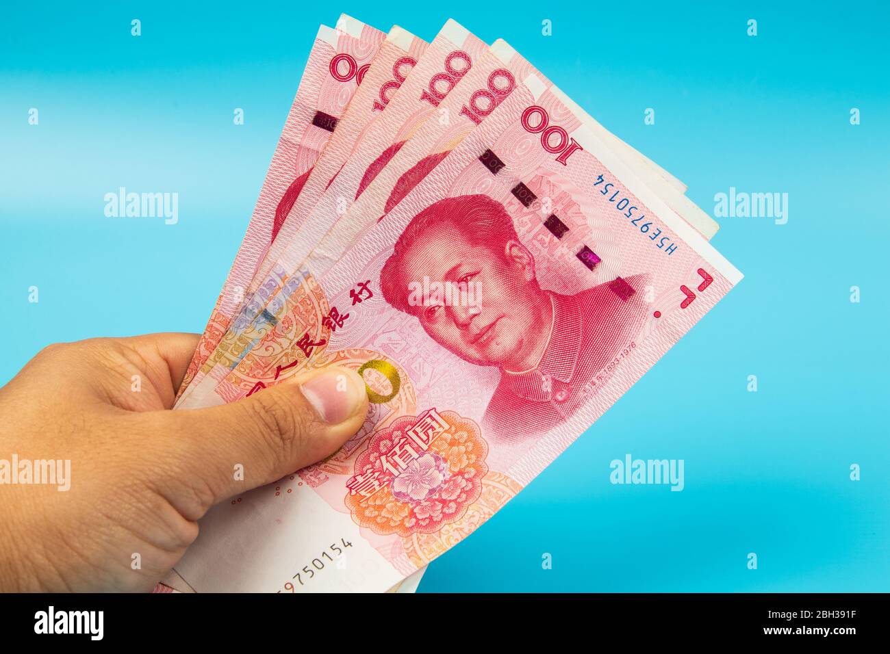 Man hand holding China Note RMB100 Yuan Note on blue background Stock ...