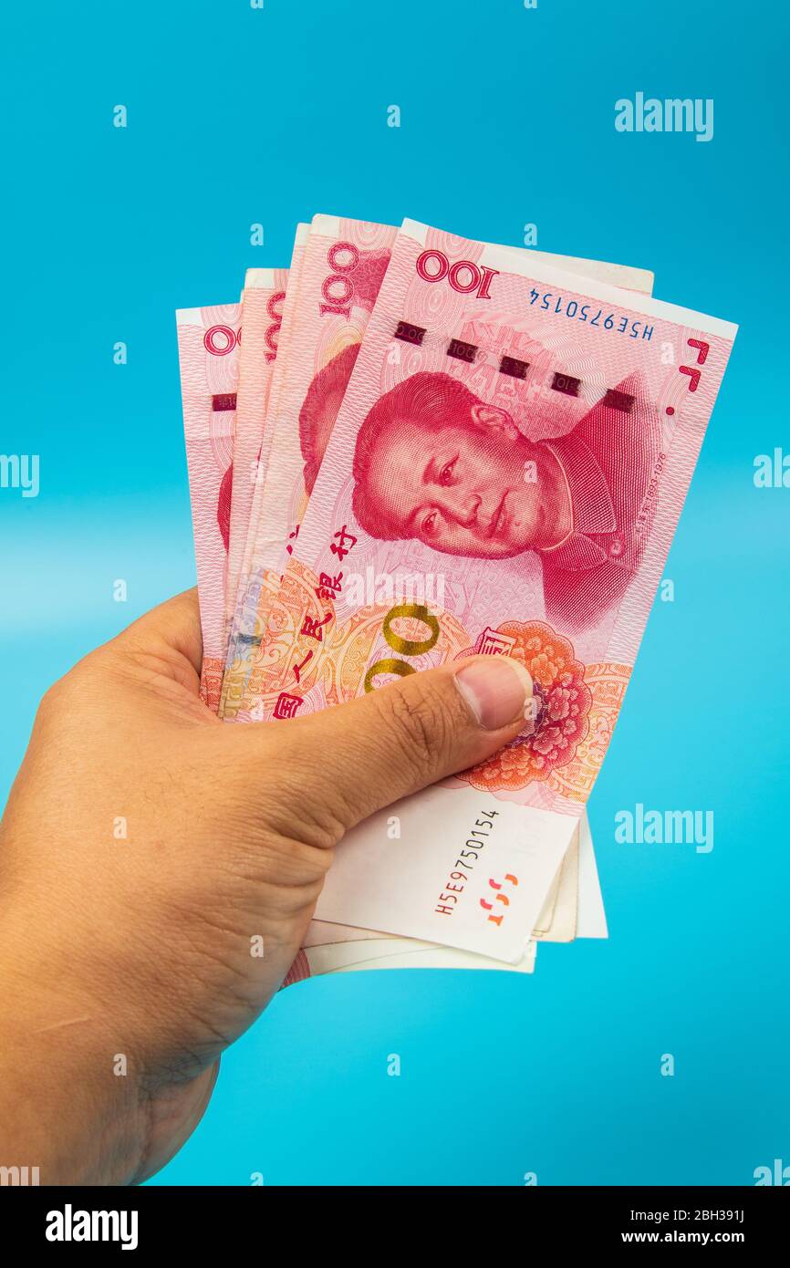 Man hand holding China Note RMB100 Yuan Note on blue background Stock ...