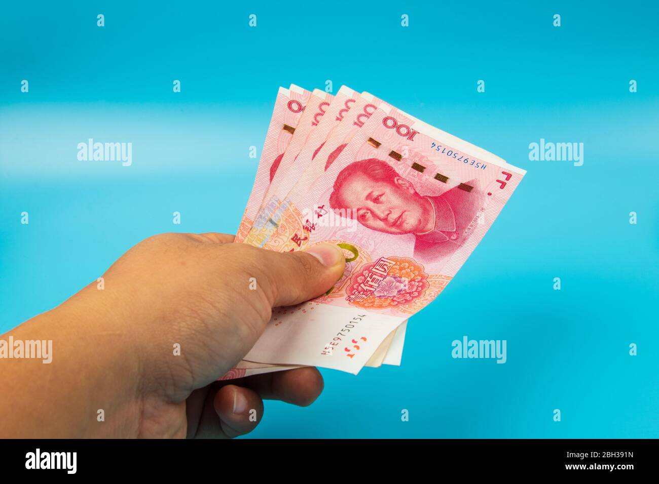 Man hand holding China Note RMB100 Yuan Note on blue background Stock ...