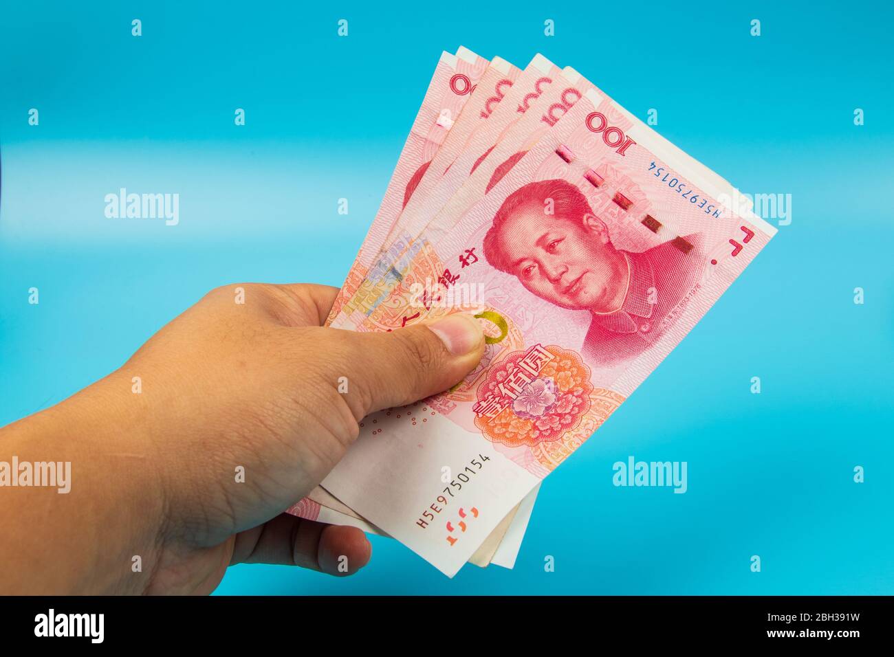 Man hand holding China Note RMB100 Yuan Note on blue background Stock ...