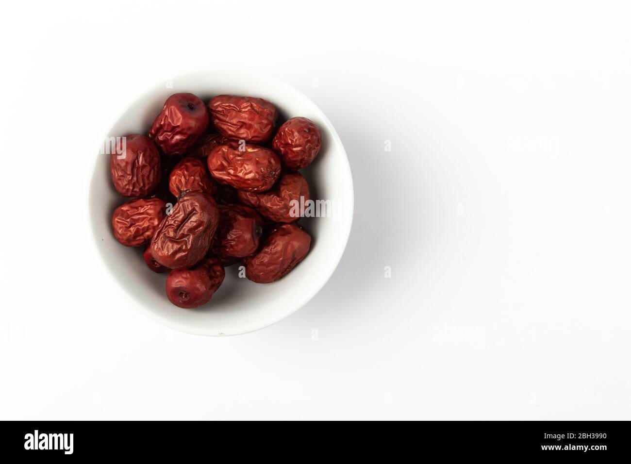 A bowl of Chinese dried red date fruit on white background. Keywords ...