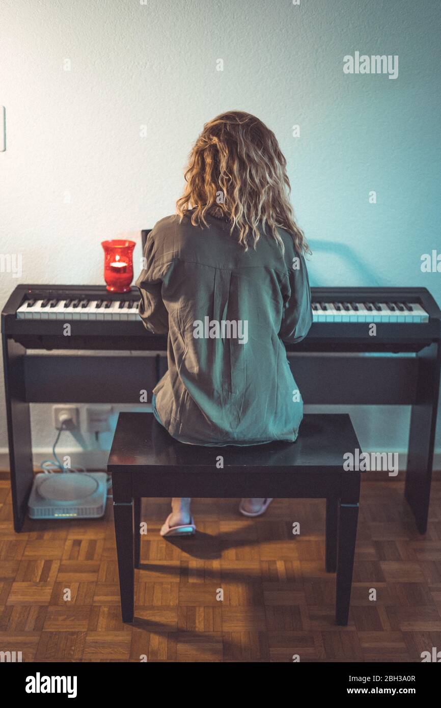 Pretty woman play the piano in home at confined days Stock Photo - Alamy