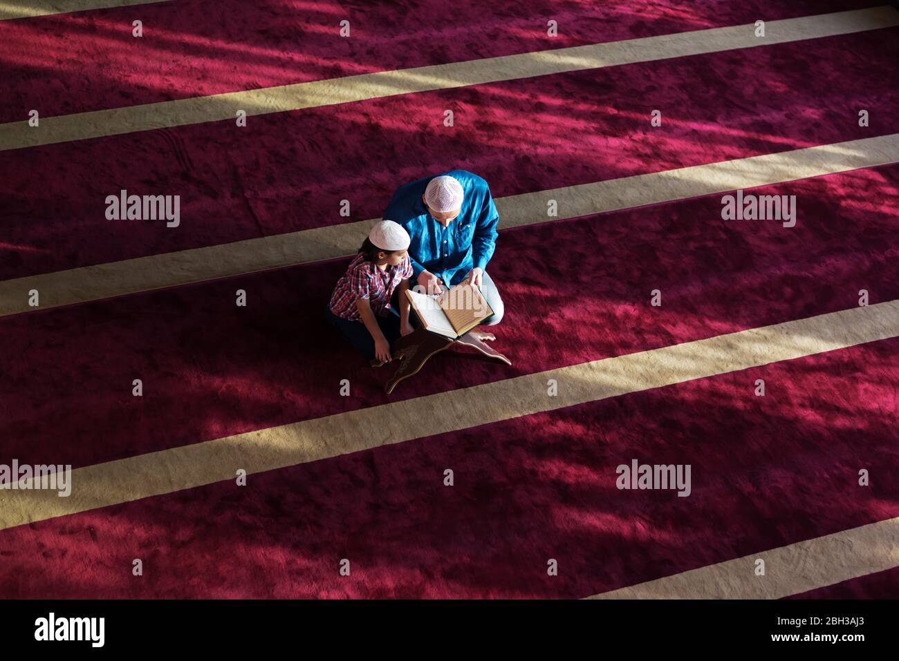 Muslim father and son praying together. Muslim dad and son praying in the mosque and reading ...
