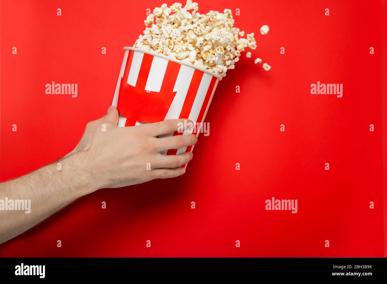 The guy holds popcorn in his hands on a red background. Place for text ...