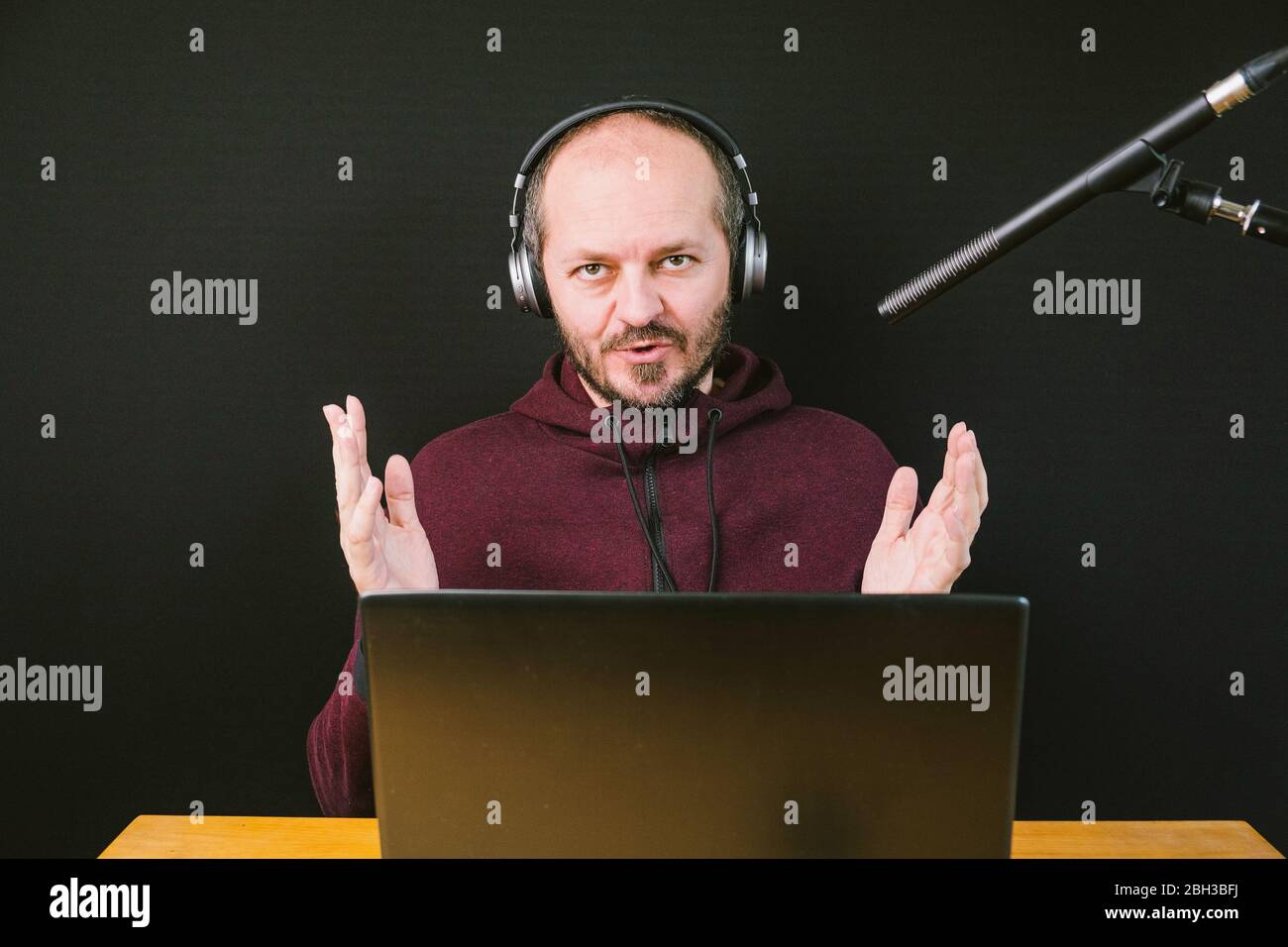 Guy in hoodie sitting behind the desk with laptop computer and ...