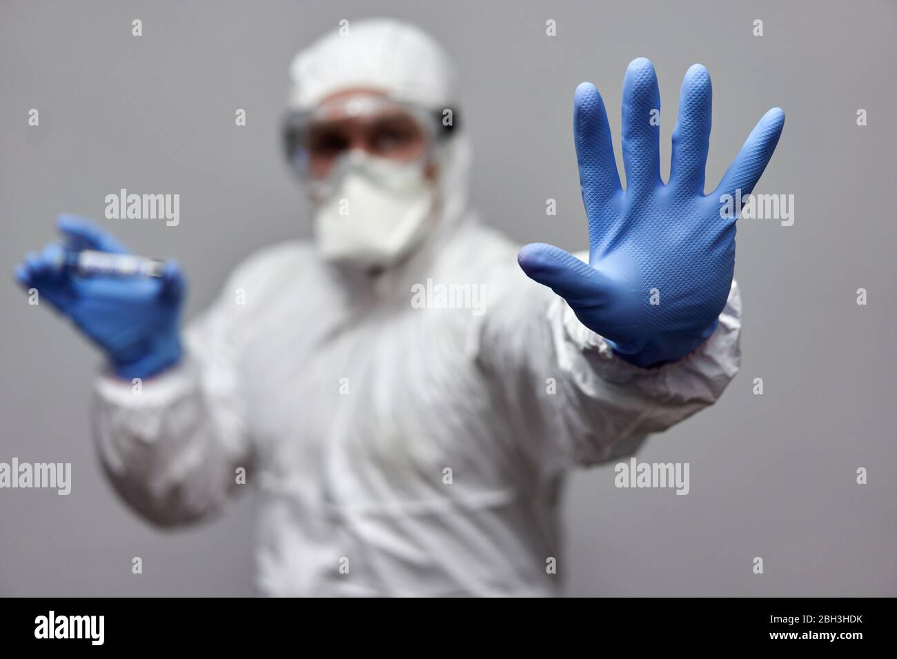 Man in overall protection suit against coronavirus making stop sign ...