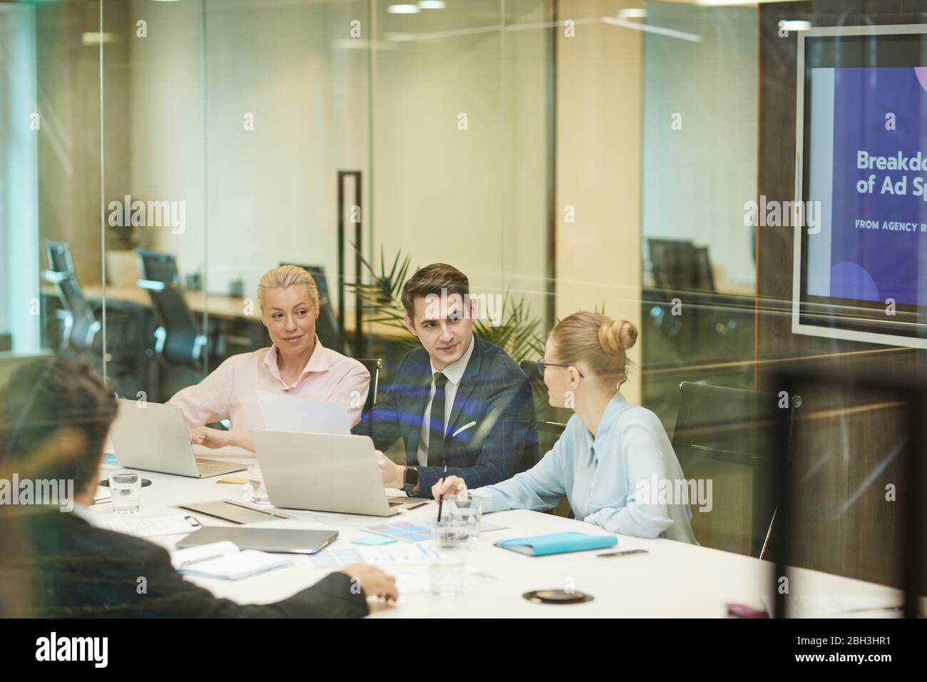 Group of business people sitting at the table with laptops and talking ...