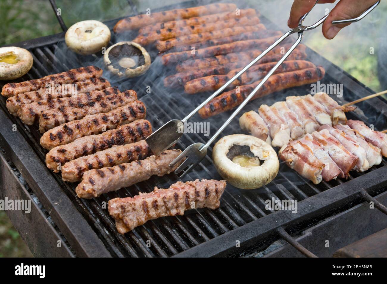 Preparing barbecue meat at picnic in nature. The meat is roasted in a ...