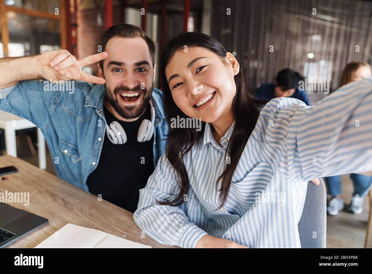 Photo of multinational cheerful students gesturing peace sign and ...