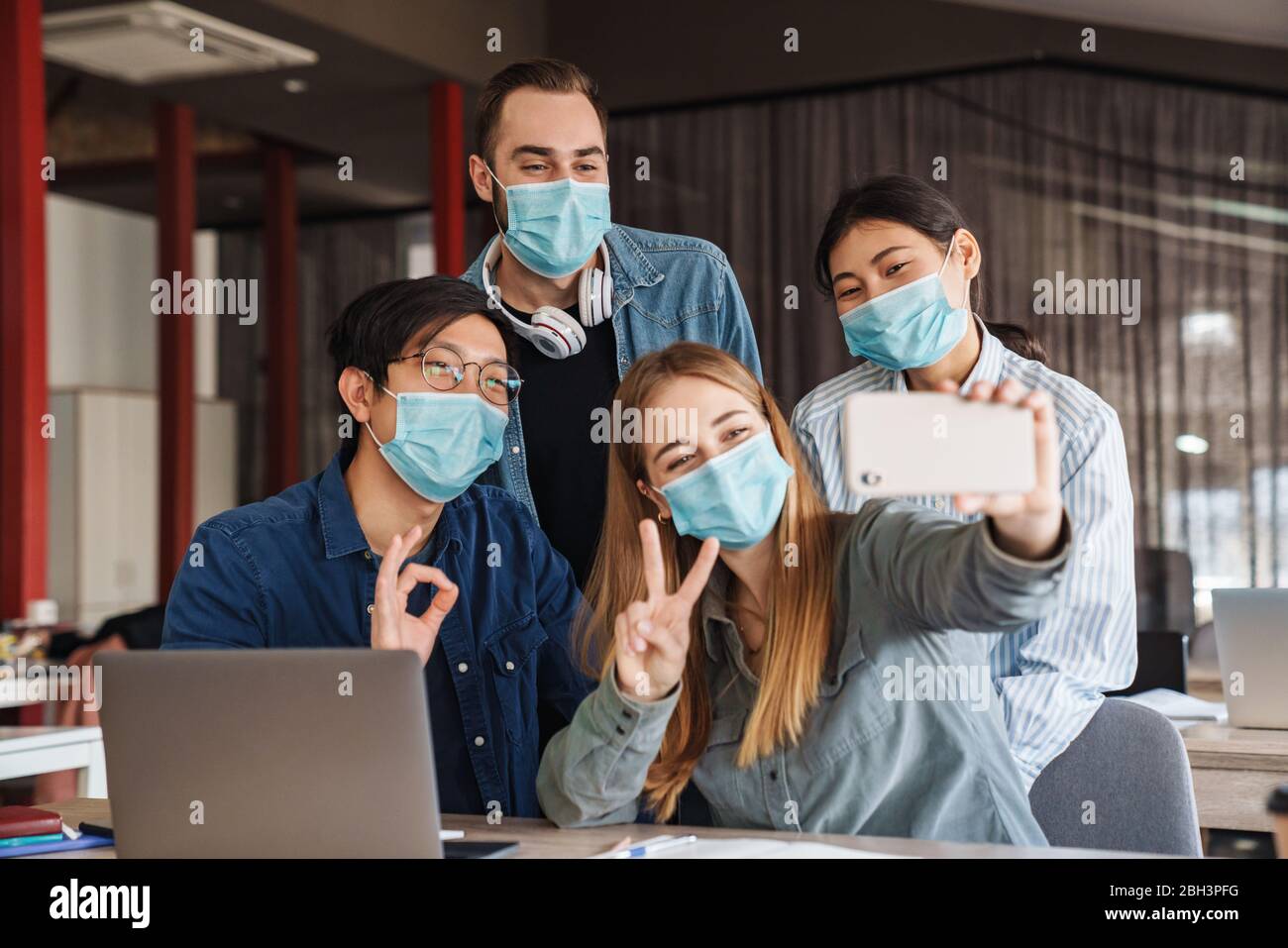 Photo of multinational cheerful students in medical masks taking selfie ...