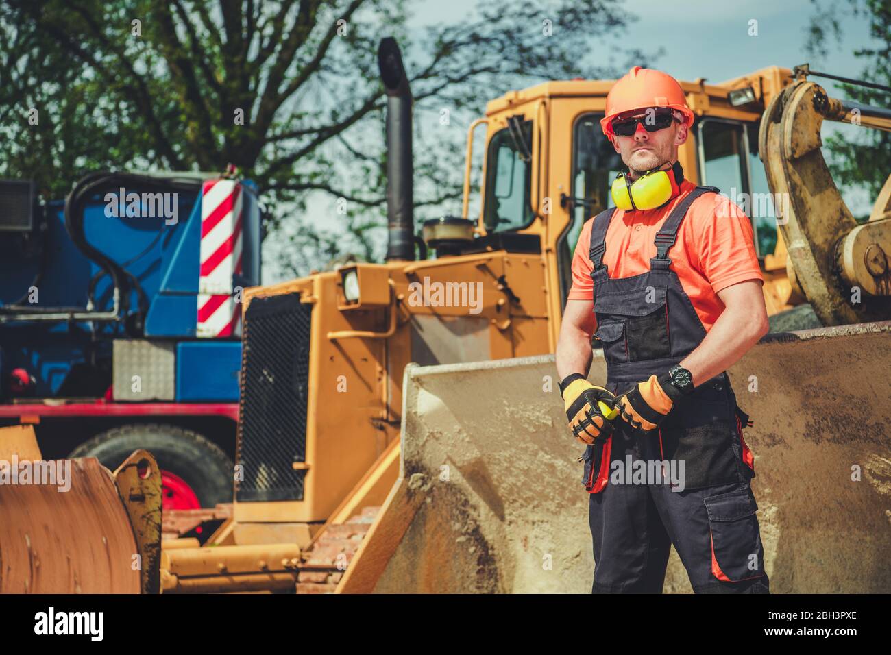 Construction Work Site With Heavy Duty Machinery And Worker With Safety ...