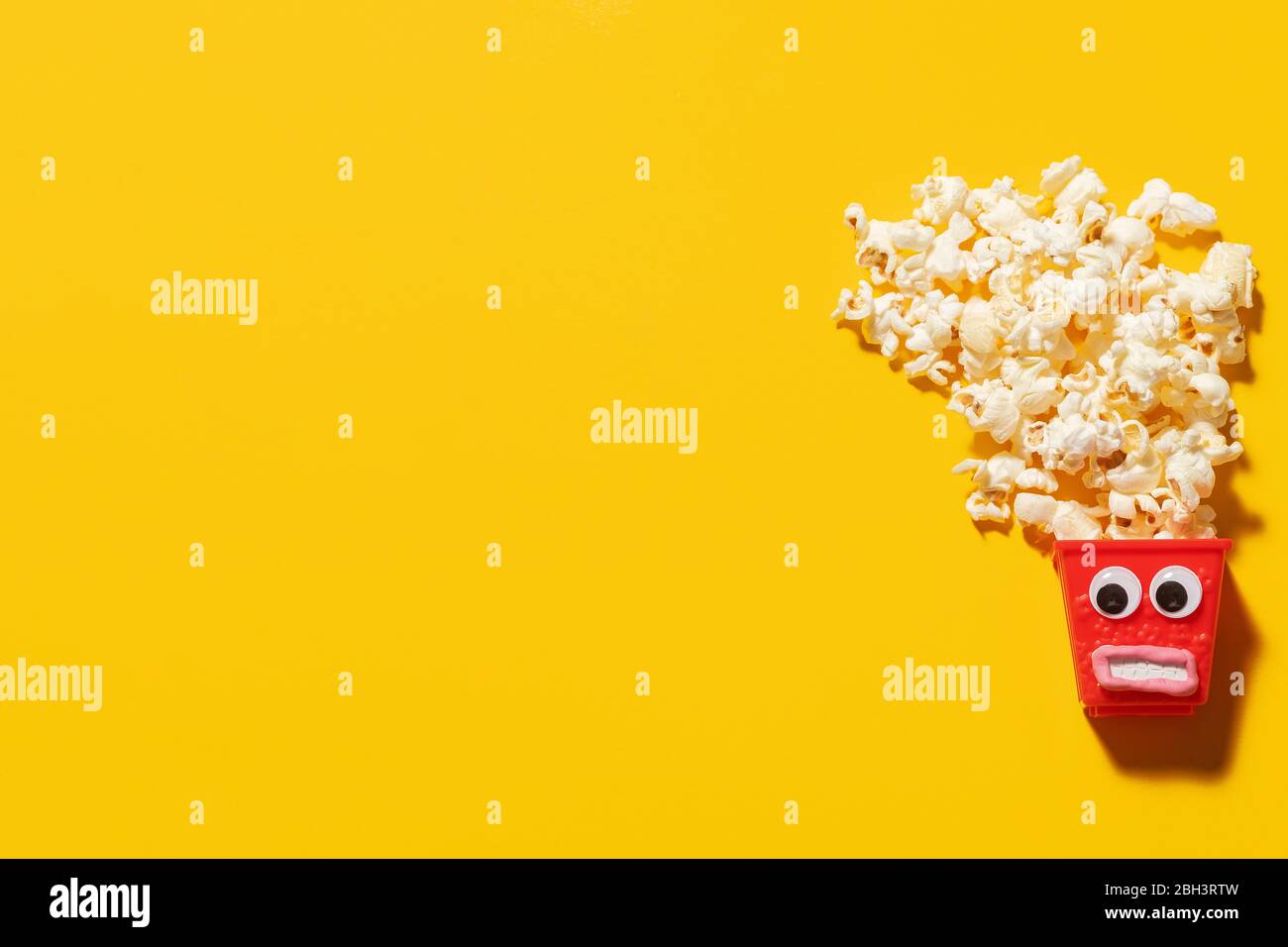 Red popcorn box carton with googly eyes and angry face with popped ...