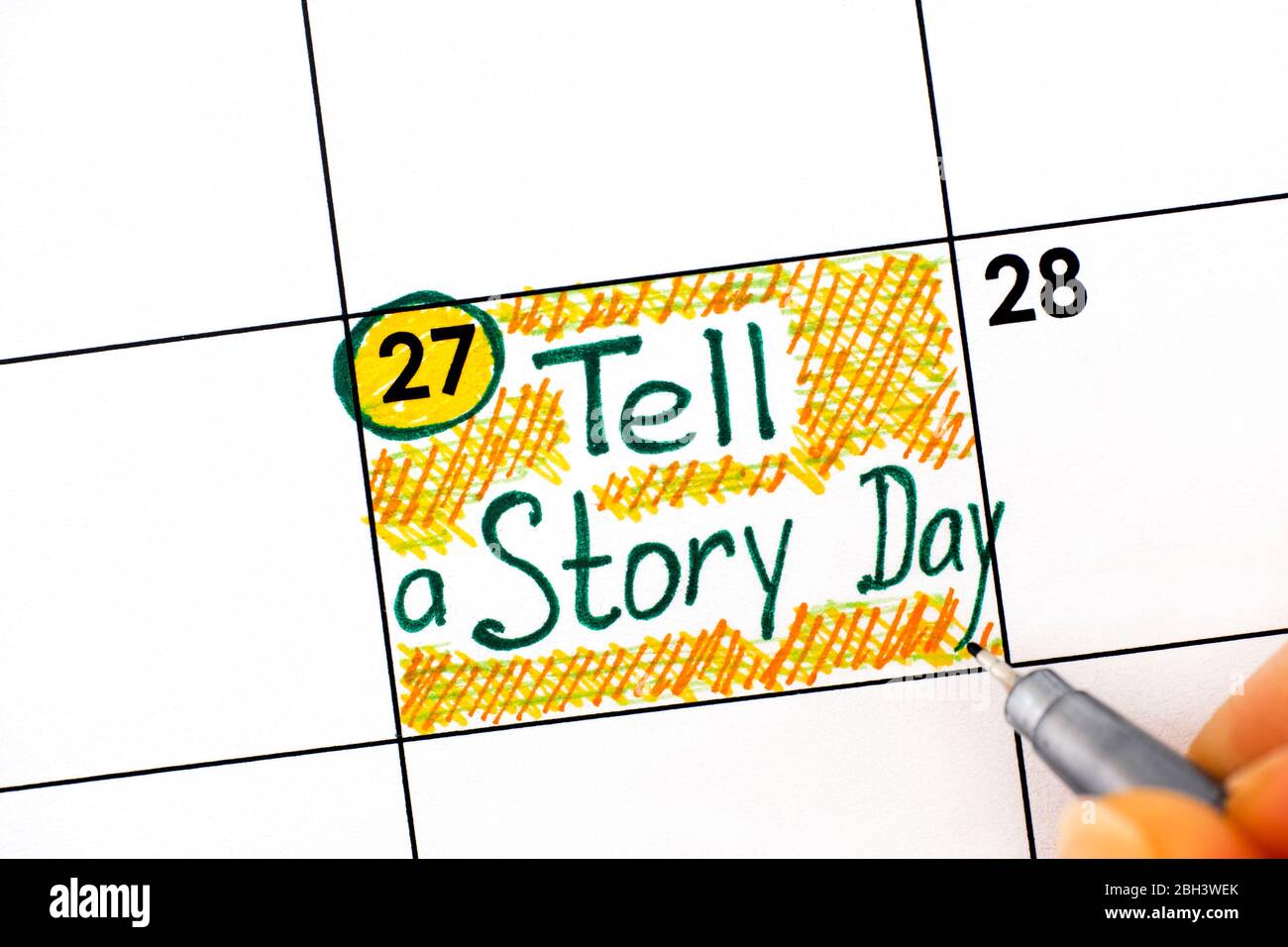 Woman fingers with pen writing reminder Tell a Story Day in calendar ...