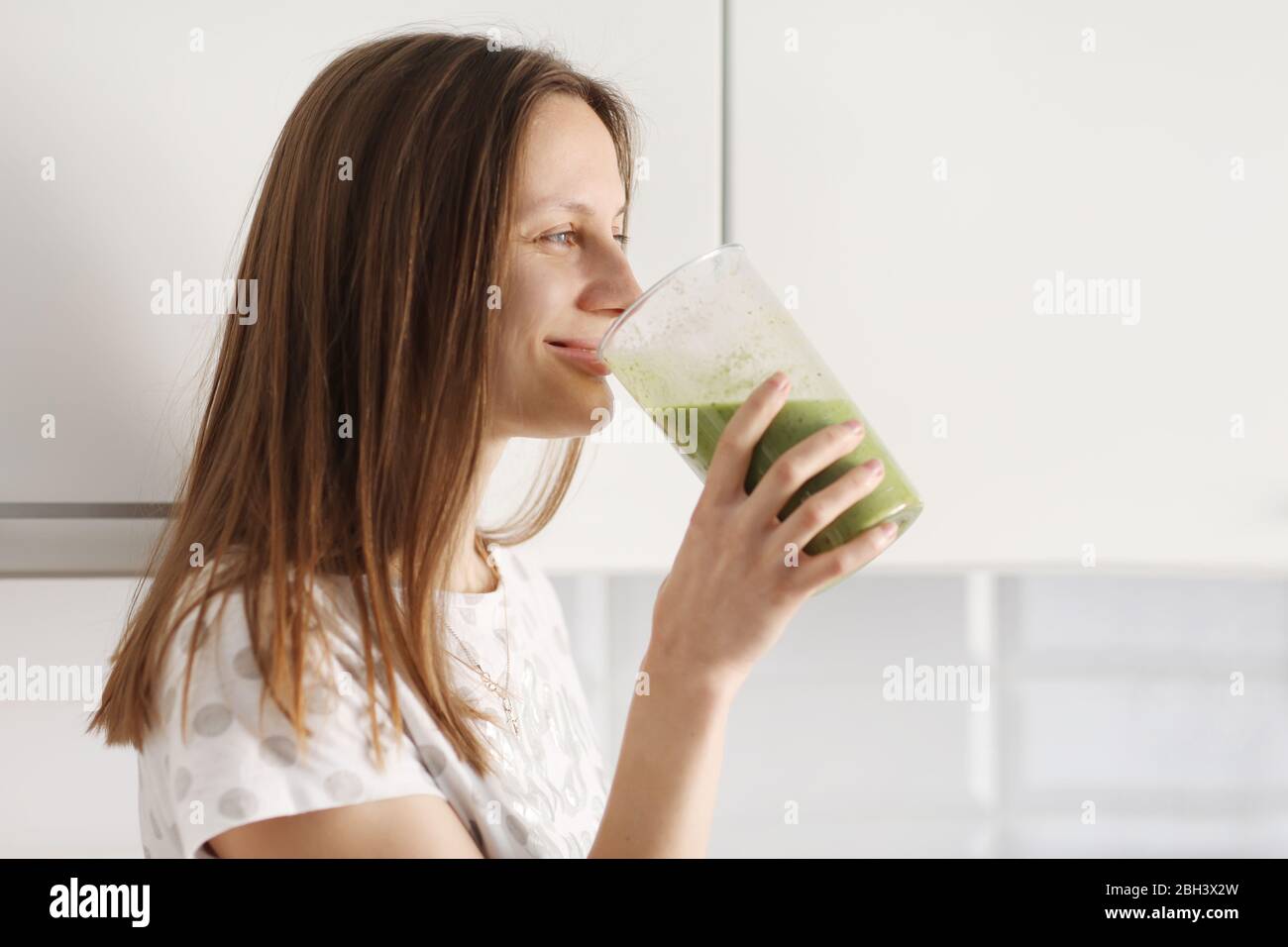 Beautiful girl drinks freshly prepared smoothie in kitchen. smoothies ...
