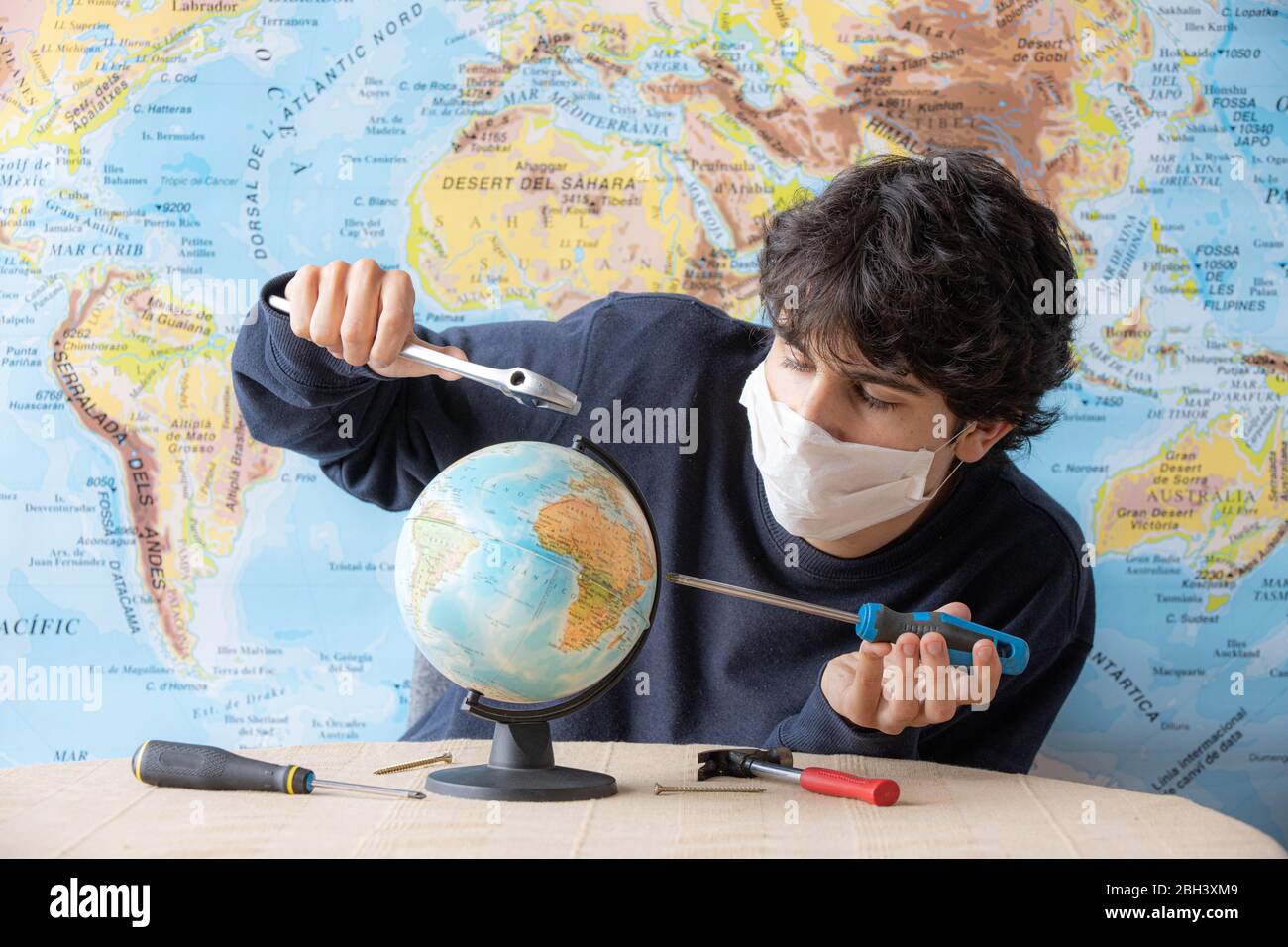 Man with mask and tools fixing a world globe with world map in the ...