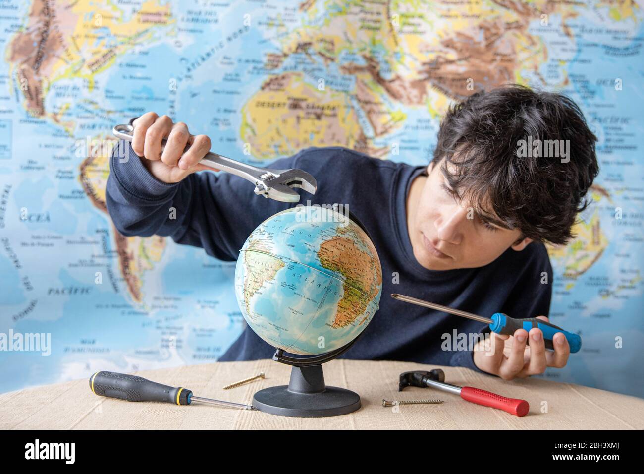 Man with tools and world map in the background fixing a world globe ...