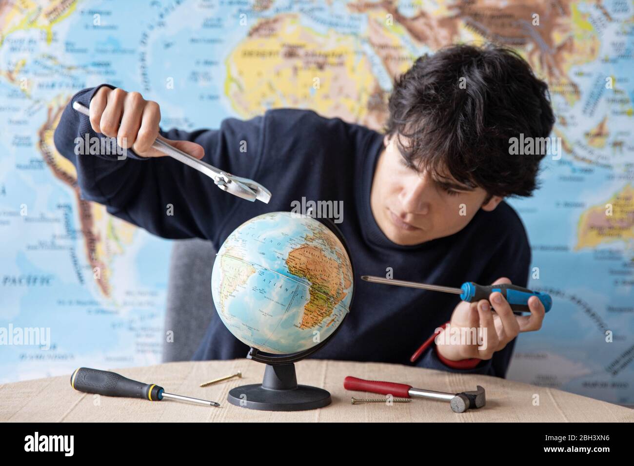 Man with tools and world map in the background fixing a world globe ...