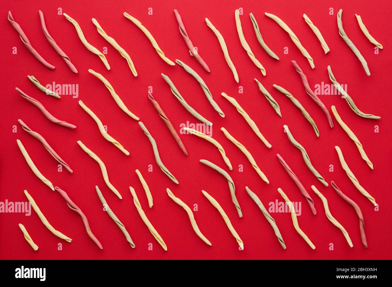 Italian fileja pasta on a red background. Flat lay photo with diagonal ...