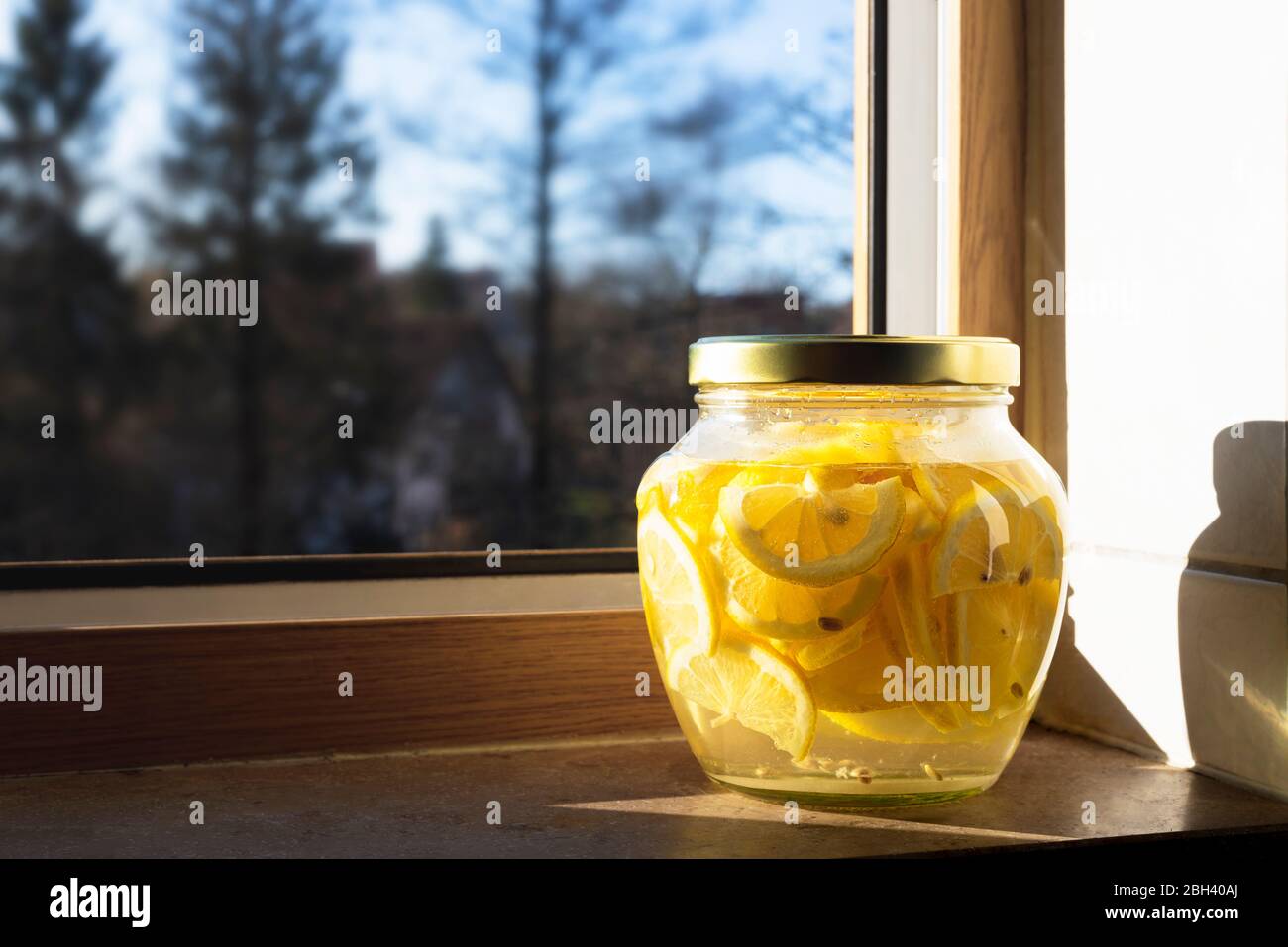 Lemonade with slices of lemons in a big jar on the kitchen window sill ...