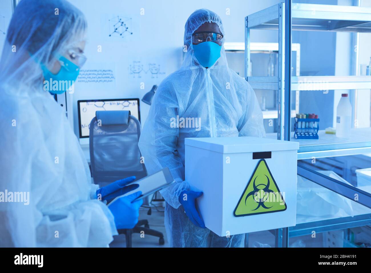 African chemist in protective workwear holding box with chemical ...