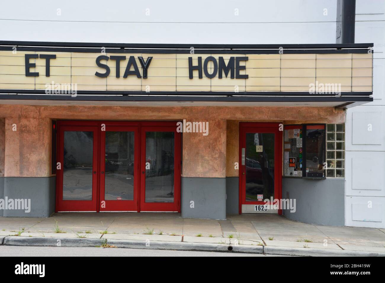 A sign reading ET Stay Home is posted on a small movie theater closed ...