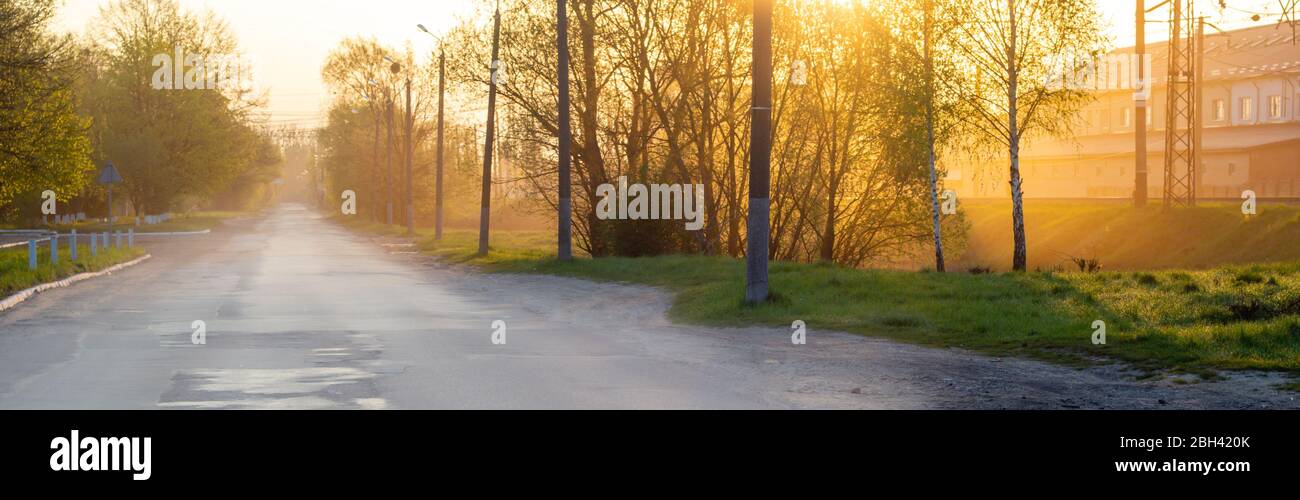 Empty concrete road in bright golden sunrise light with nature ...