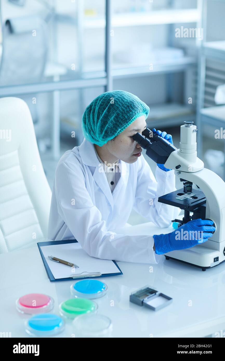 Female scientist sitting at her workplace and examining samples using ...