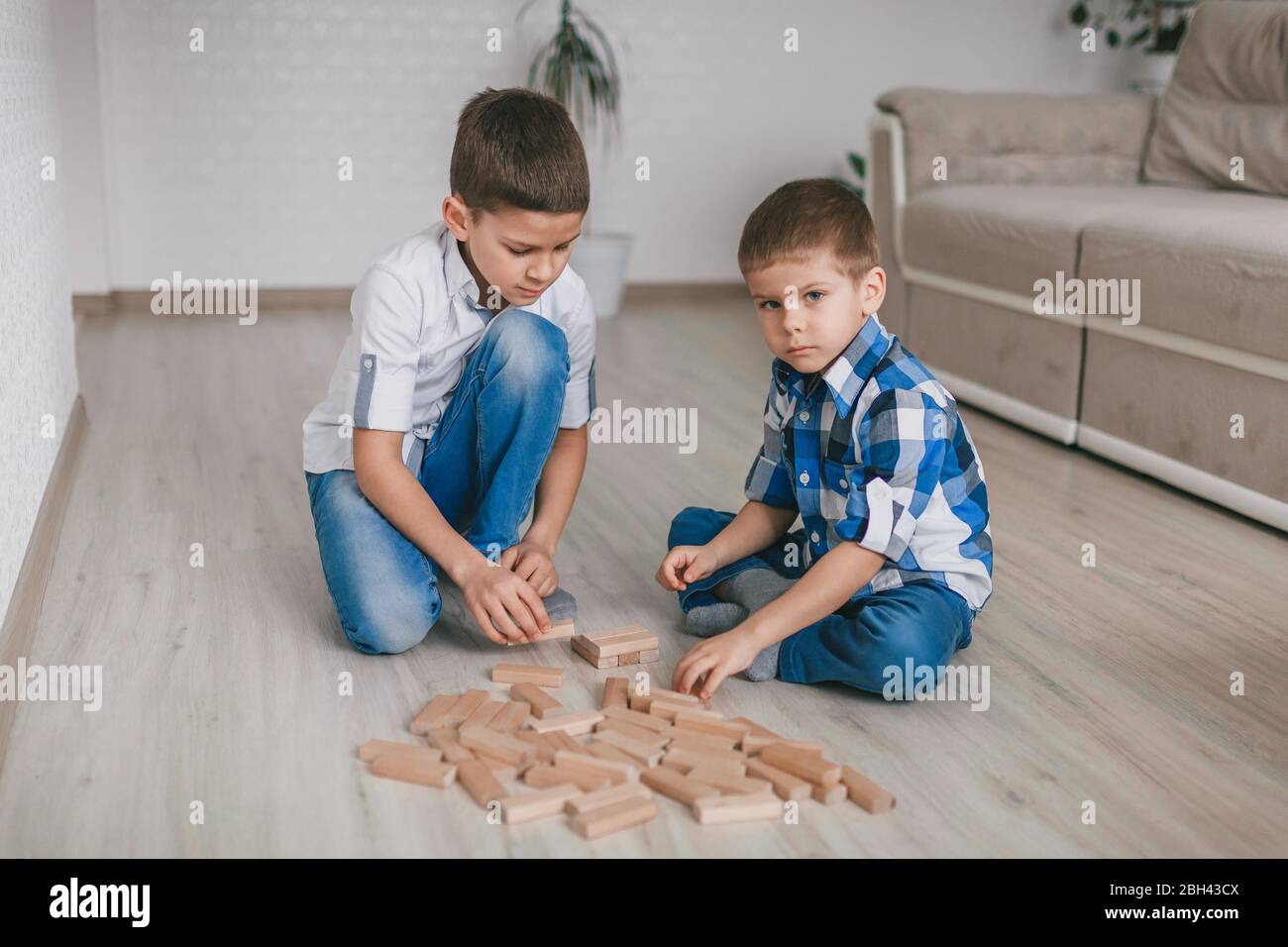 Two brothers boys build a tower of wooden blocks of the house on the ...