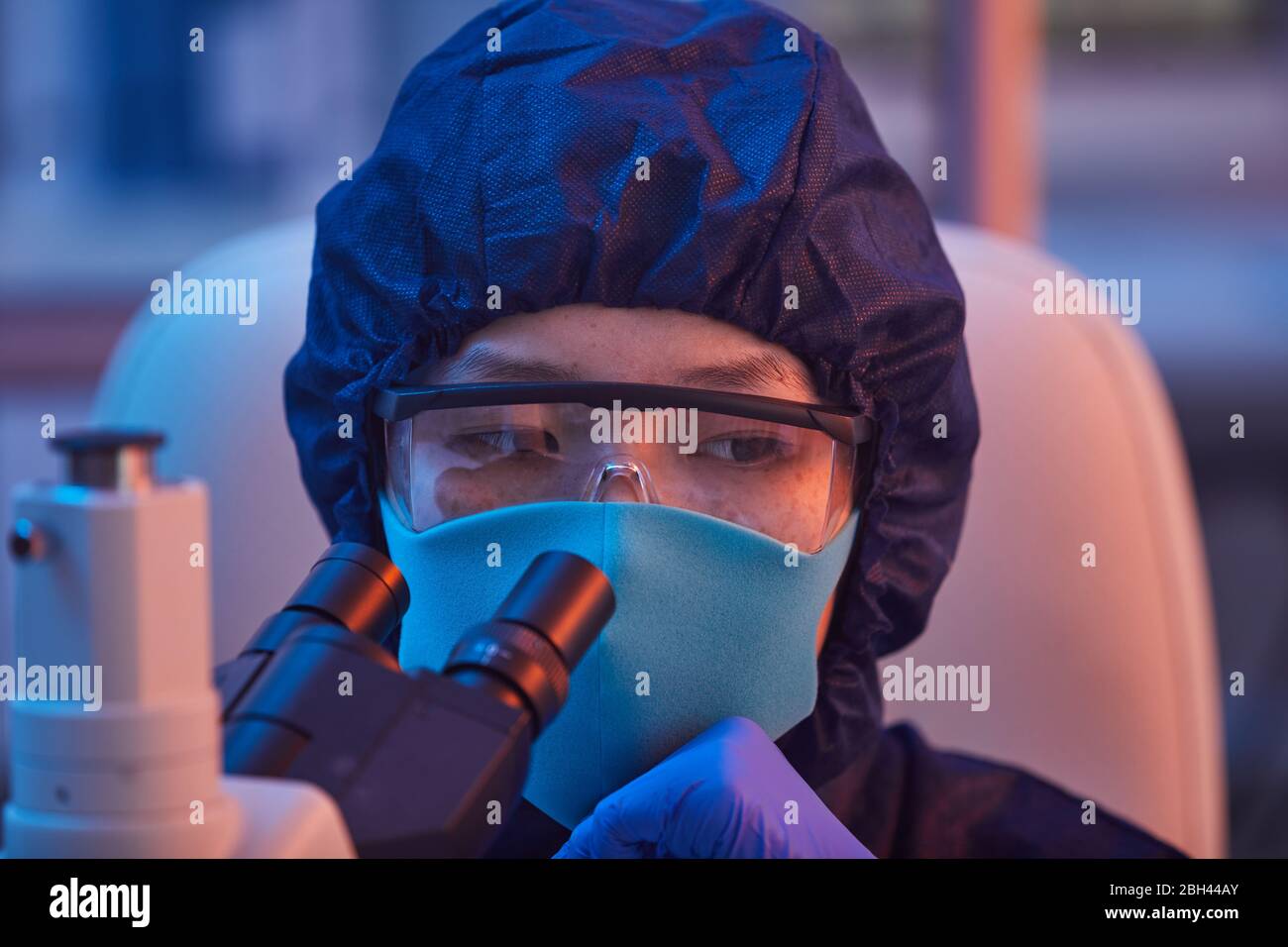 Close-up of female scientist in protective mask and glasses looking ...
