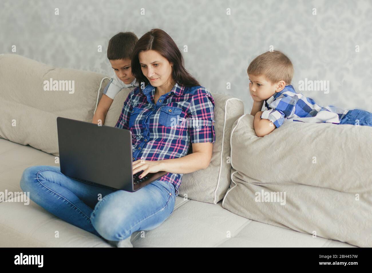 Stay at home, mom and her children watching a video conference on a laptop. Homeworking The ...