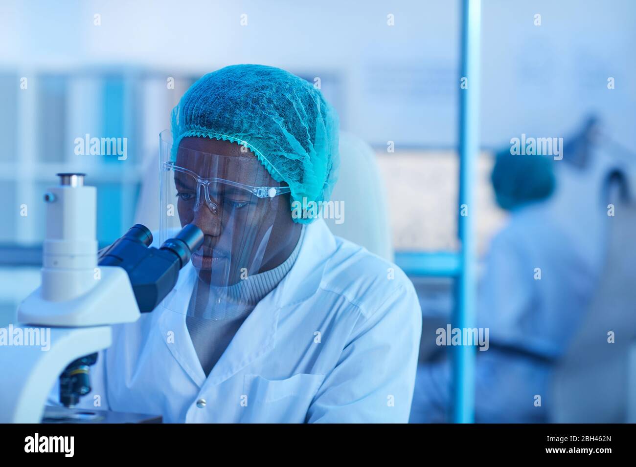 African doctor examining analysis with microscope at the laboratory ...