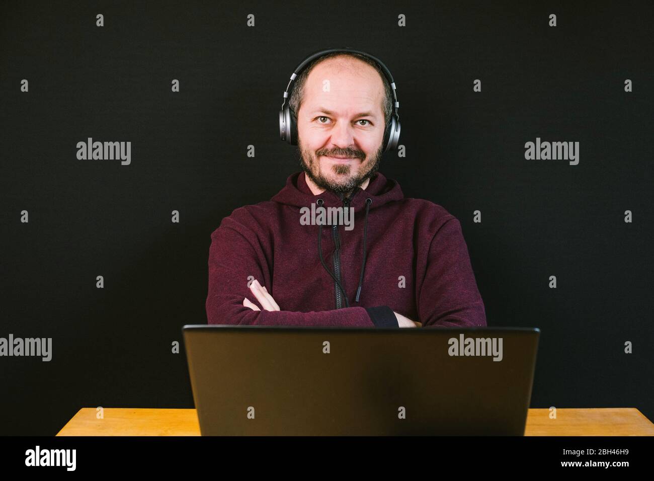 Guy in hoodie sitting behind the desk with laptop computer and ...
