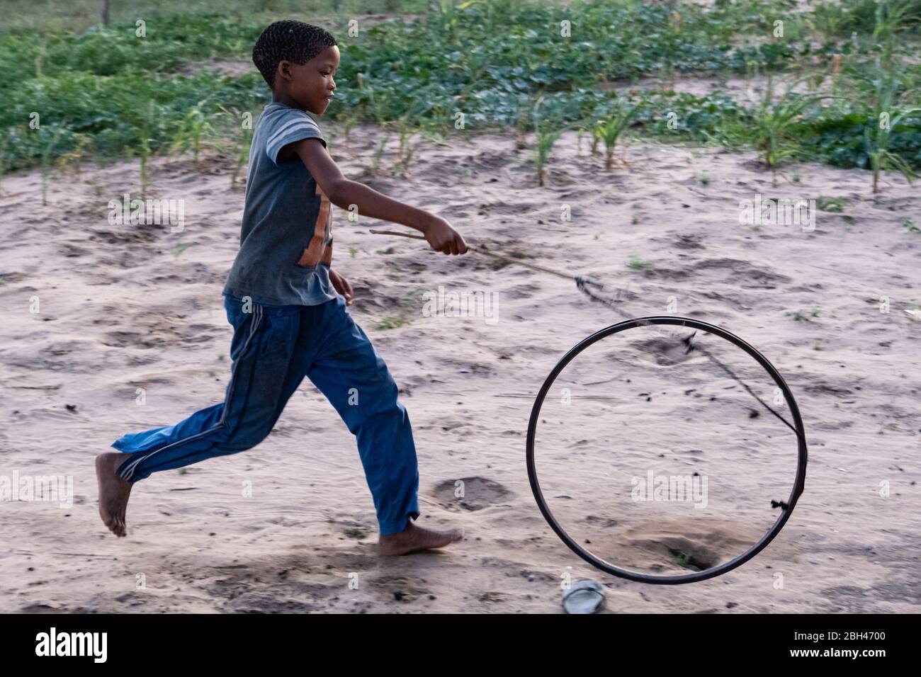 A young Ju/hoansi (San/Bushmen) boy plays in the sand of the Kalahari ...