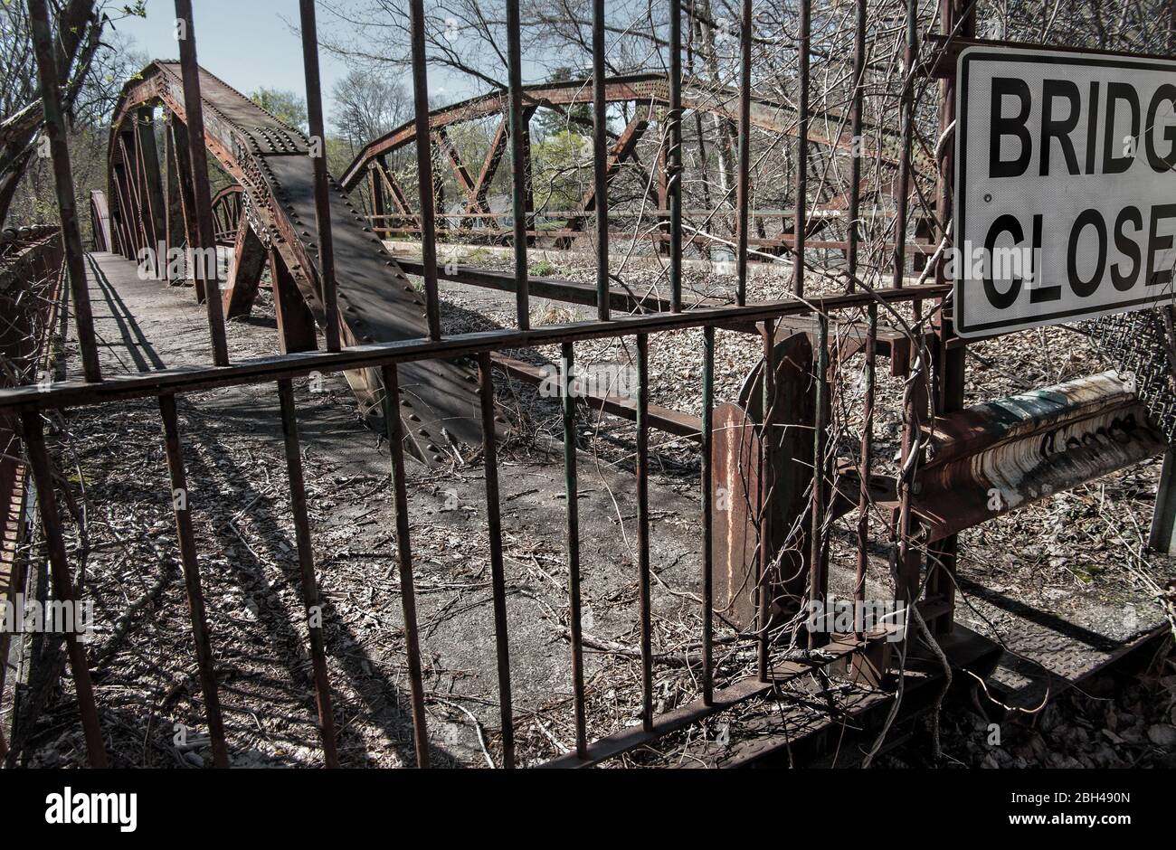 Closed Bridge: Trees and vines encroach upon a rusting, abandoned ...