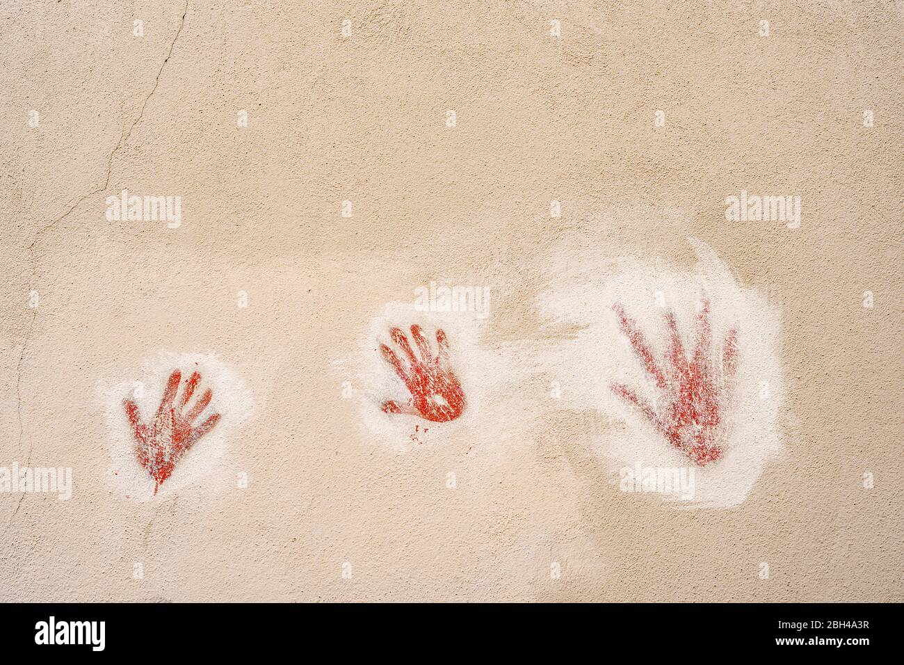 Red handprints on the wall. Two children's handprints and one adult ...