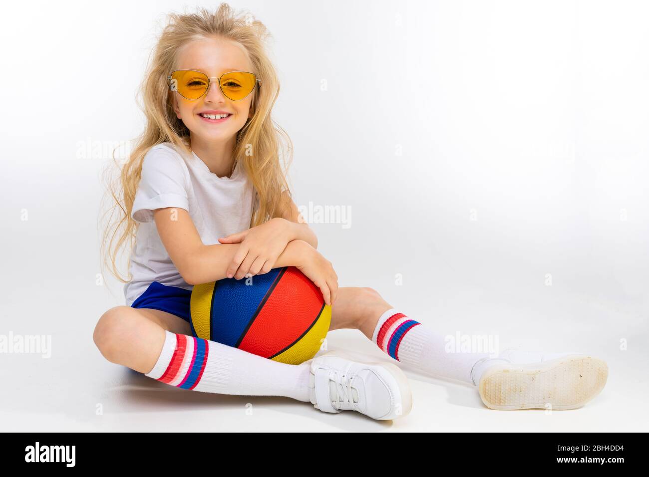 teenager girl in sports shorts with a basketball on a white background ...